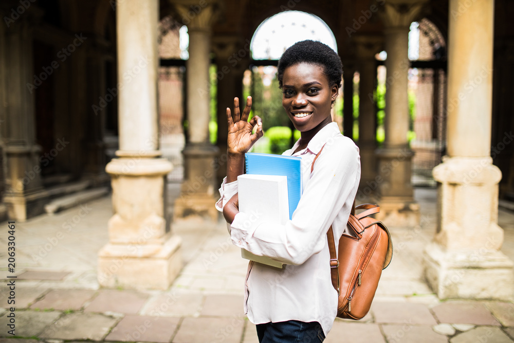 Portrait of a cheerful smiling african student girl waving and wearing ...