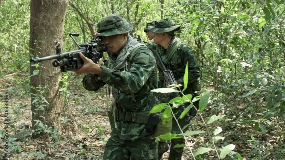 Slow motion of soldiers aiming their assault rifles in jungle. Chinese ...
