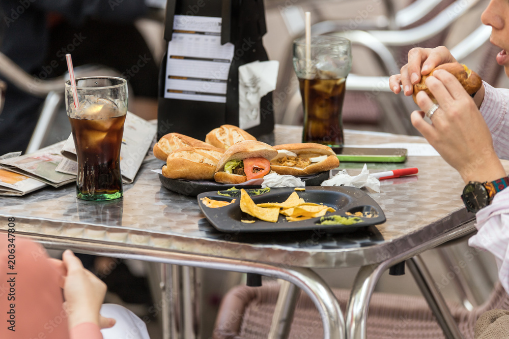 Girls sitting at a table eating a snack and drinking soda from cola ...