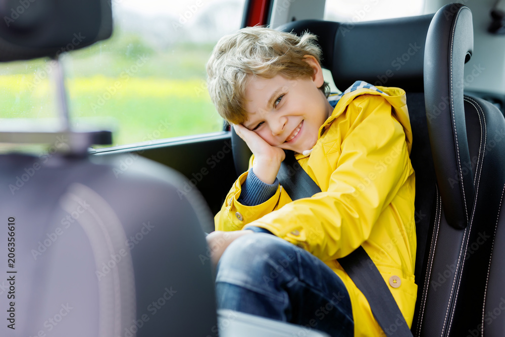 Adorable cute preschool kid boy sitting in car in yellow rain coat ...