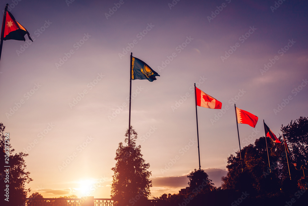 A row of flying flags of nations on sunset sky background. Flags of ...