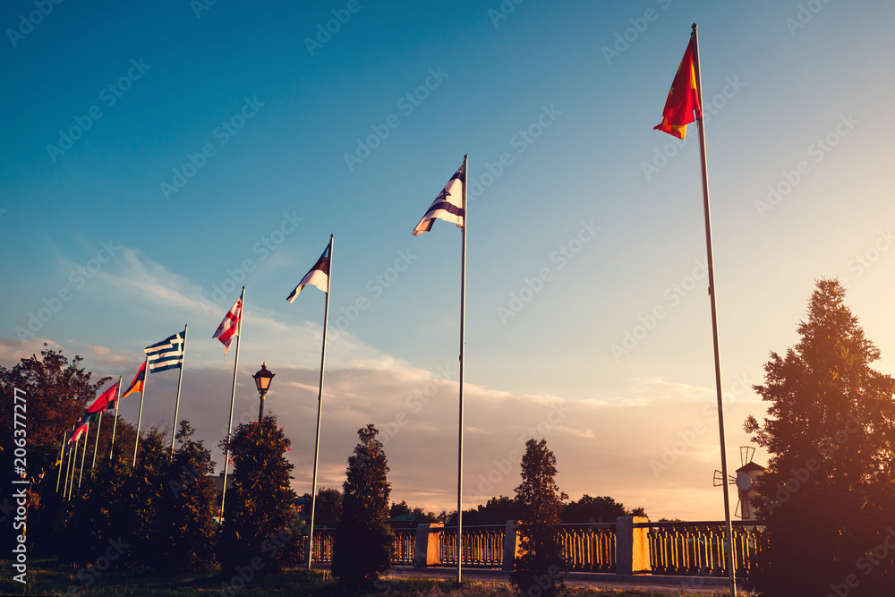 A row of flying flags of nations on sunset sky background. Flags of ...