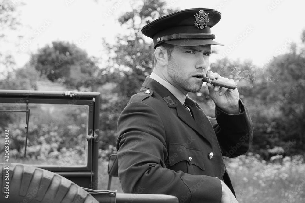 Handsome American WWII GI Army officer in uniform smoking cigar next to ...