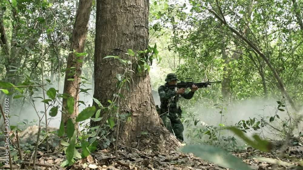 Slow motion of soldiers aiming their assault rifles in jungle. Chinese ...