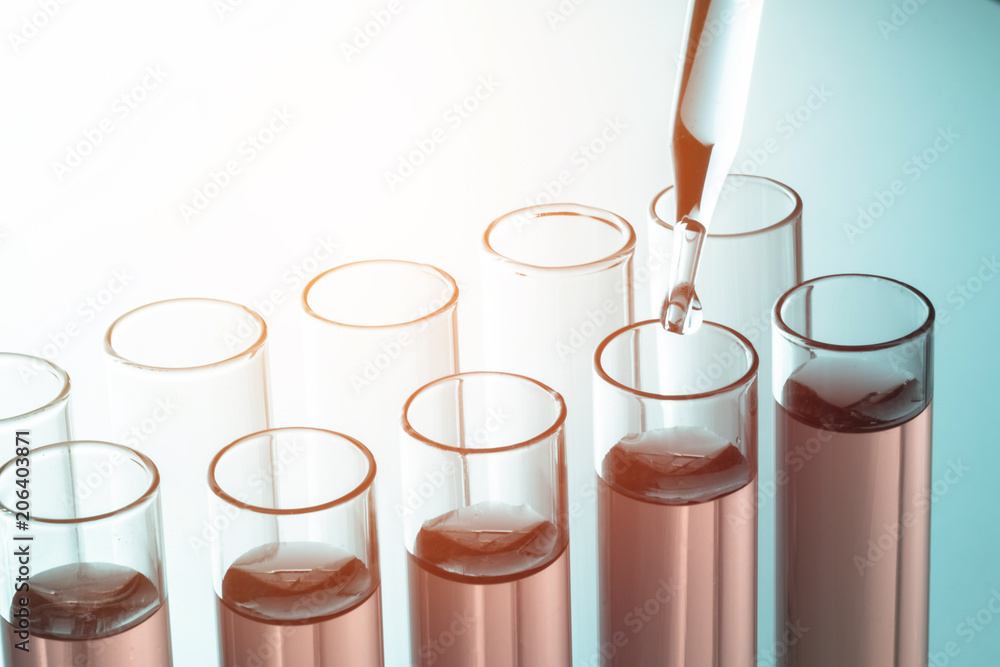 Pipette over laboratory test tube in rack dropping sample chemical for ...