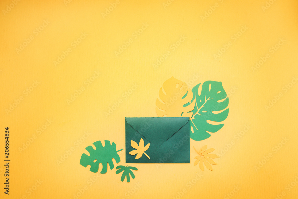Green invitation envelope with tropical leaves on a bright yellow ...