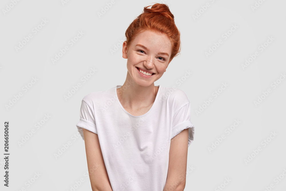 Portrait of positive glad ginger young female has warm smile, shy look ...