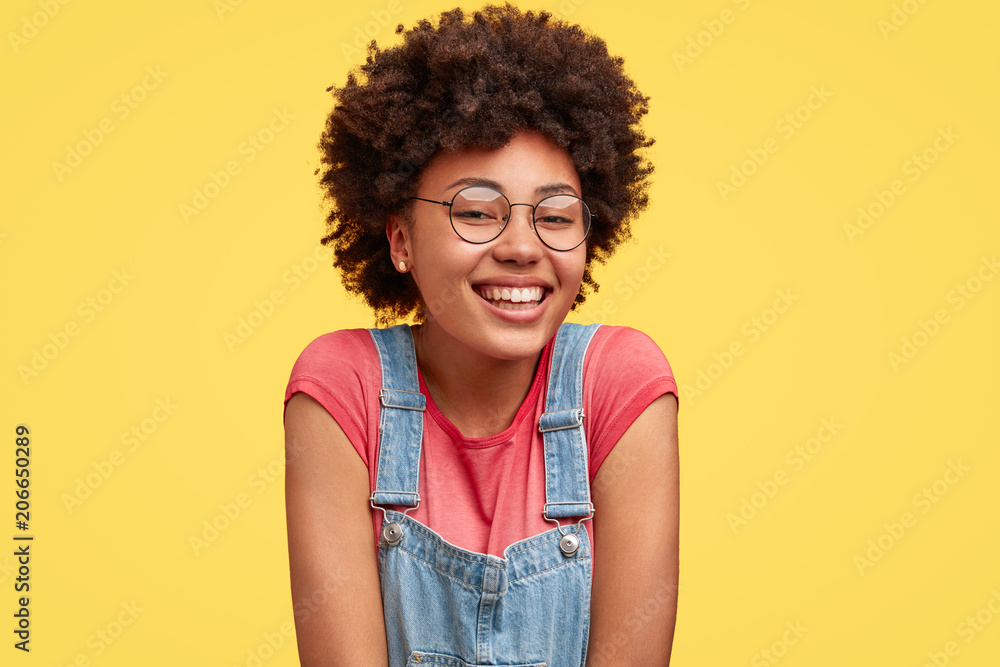 Positive glad African American female has broad smile, wears spectacles ...