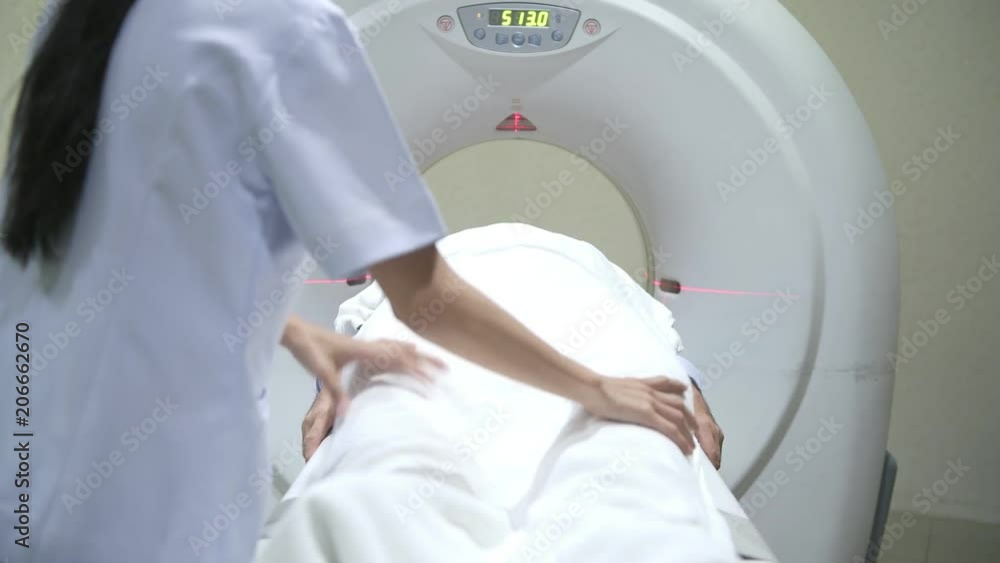 Patient getting up after finishing CT scan using MRI machine. Senior ...
