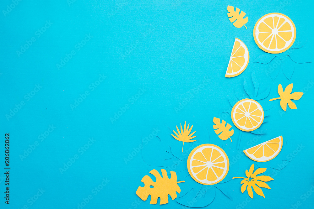 Frame with orange slices and tropical leaves pattern on a bright blue ...