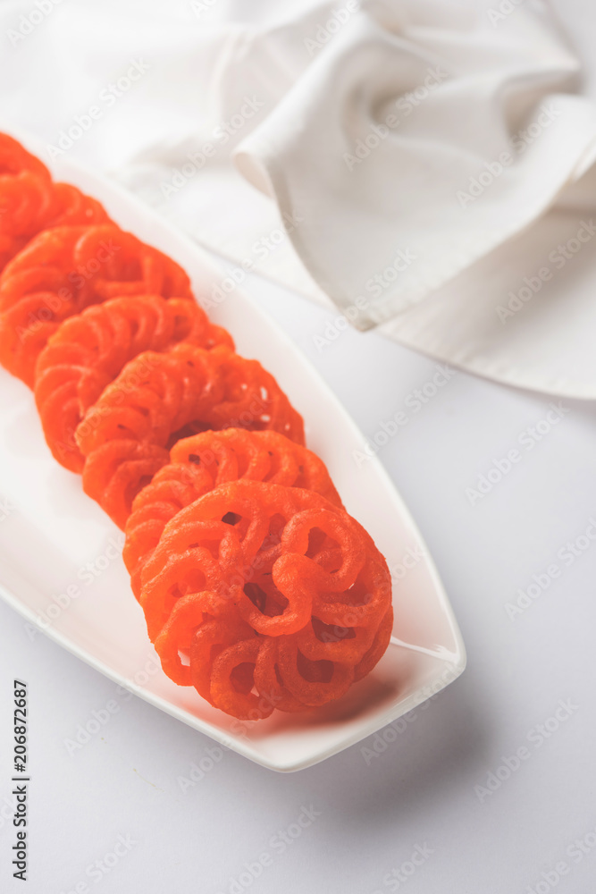 Indian sweet Imarti or Jalebi served in white ceramic plate over white ...