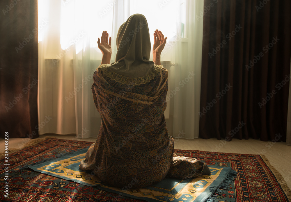 Muslim woman praying for Allah muslim god at room near window. Hands of ...