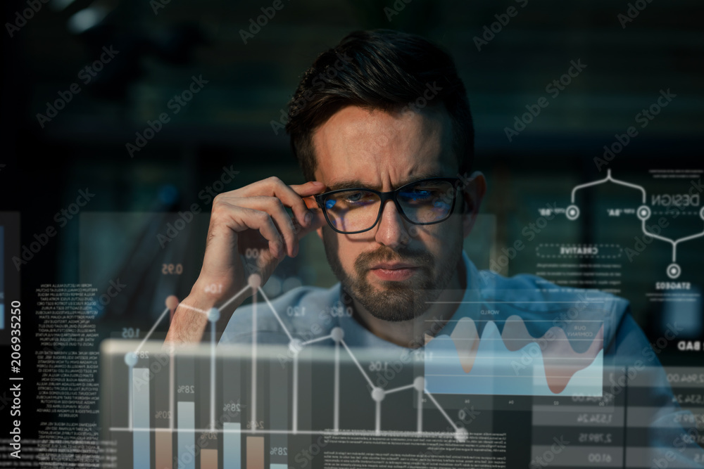 Man in eyeglasses watching monitor of computer sitting alone late at ...