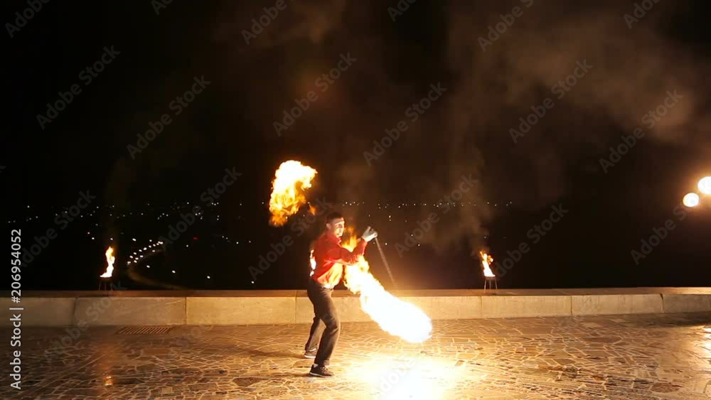 Artist man rotates the fireball.Man twist fiery circles on a fire show ...