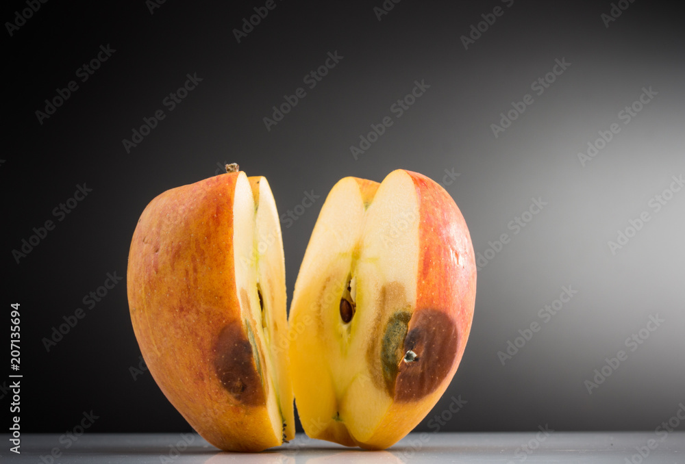 aufgeschnittener Apfel mit brauner Stelle und grünem Schimmelpilz im ...