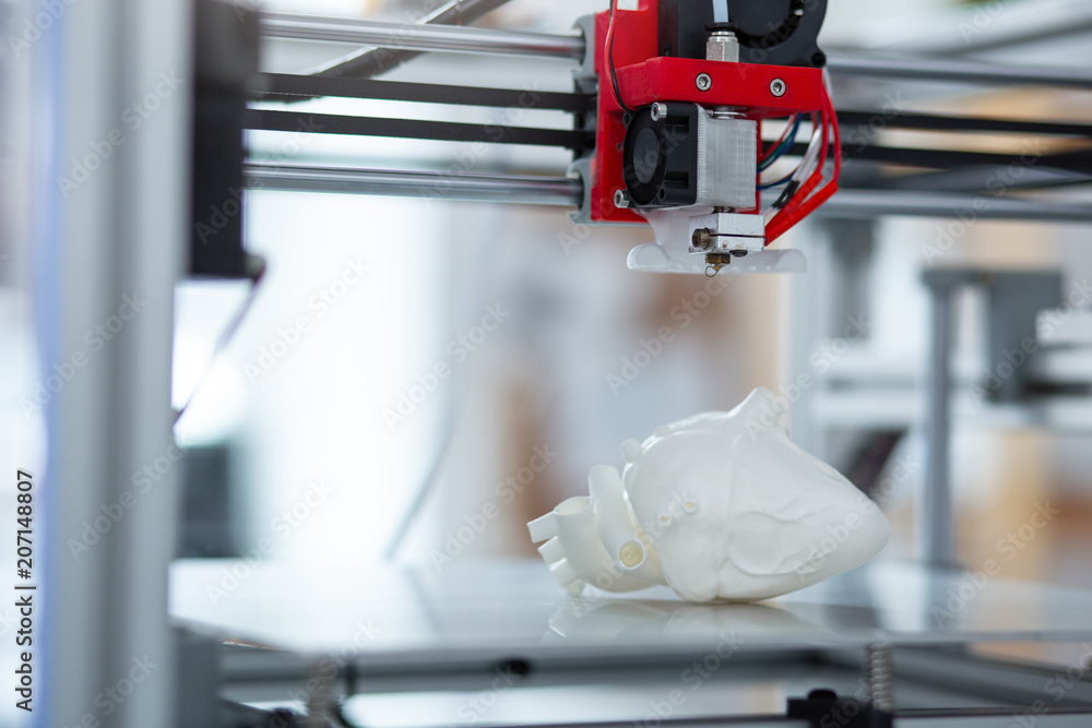 Exact replica. The close up of a 3D printer creating a model of heart ...