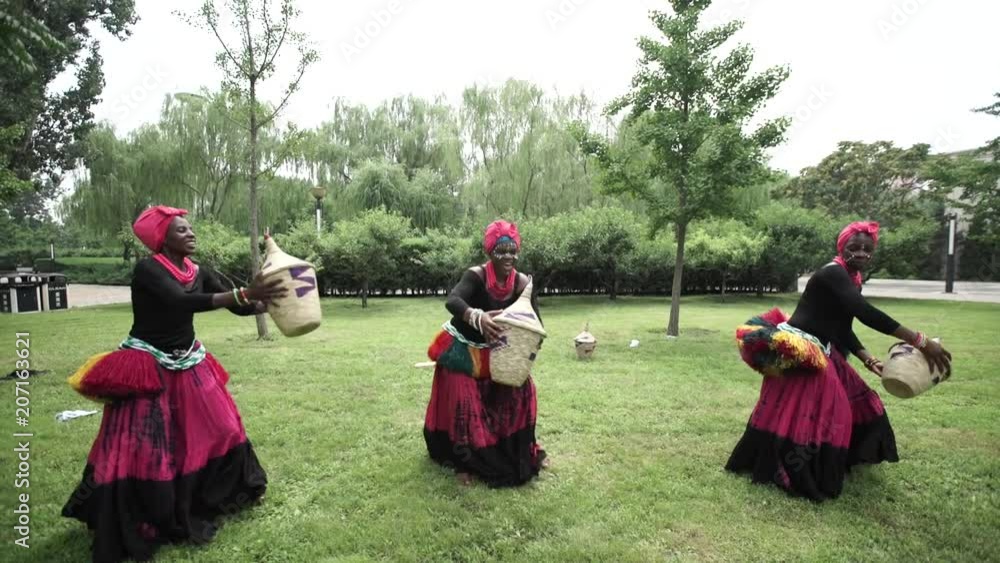 African women are dancing a folk traditional dance on a grass meadow ...