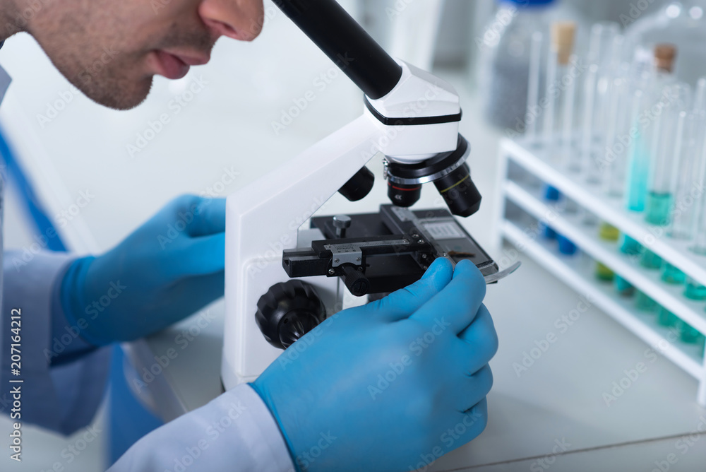 Adult unshaken explorer sitting and using the microscope. Stock Photo ...
