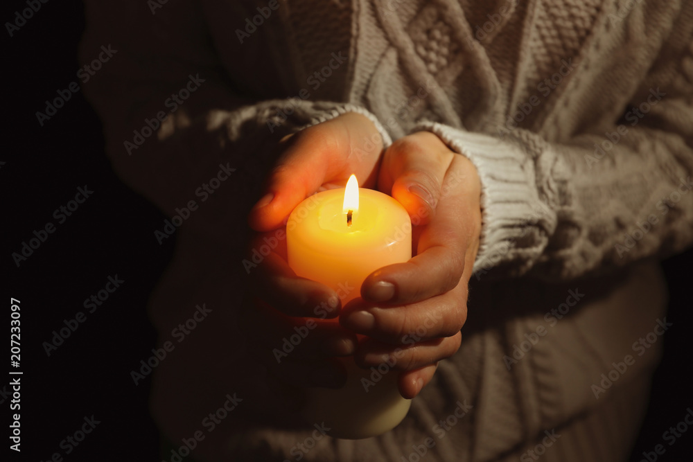 Young person holding burning candle in darkness, closeup Stock Photo ...