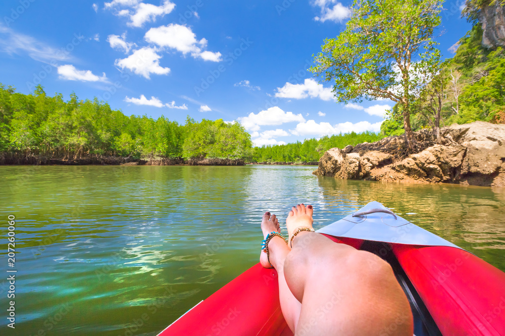 Closeup of tanned and sexy woman's legs with anklets on a red kayak in ...