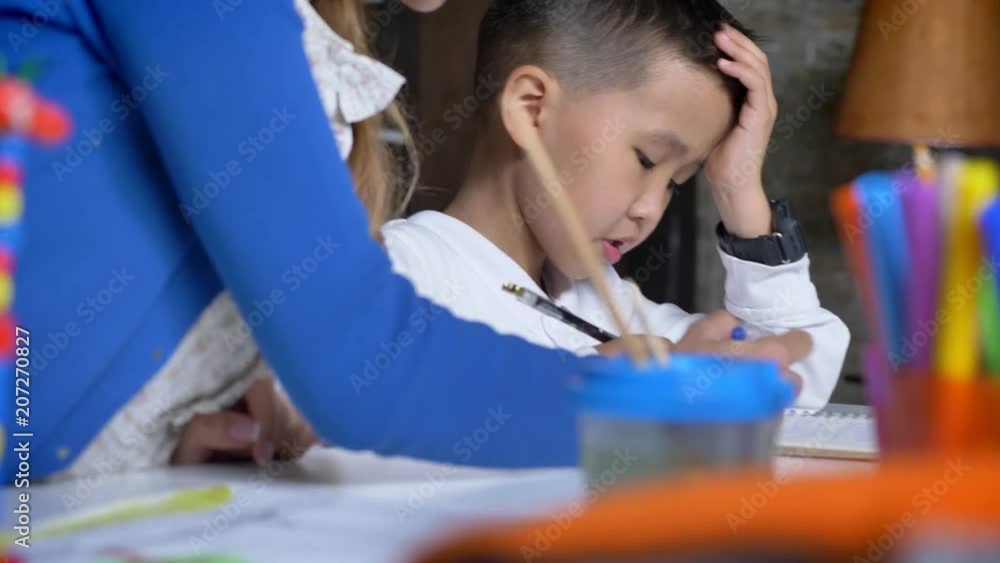Asain young mother explaining to son, helping kid with homework ...