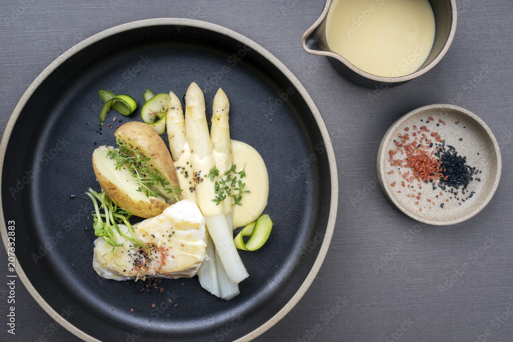 Modern German fried cod fish filet with white asparagus in hollandaise ...