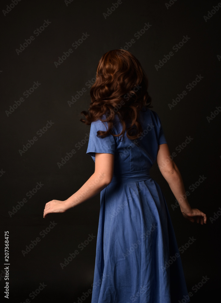 3/4 portrait of brunette lady wearing blue dress, facing away from ...