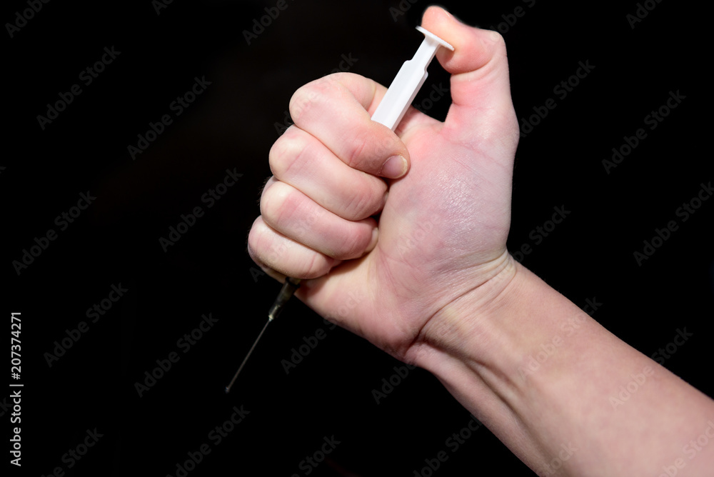 Syringe in hand on black background. Drug addict hands holding syringe ...