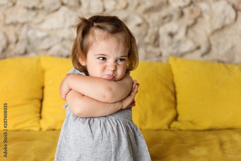 Toddler girl pouting with funny face on yellow couch Stock Photo ...