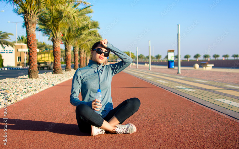 Girl sitting on a running track and enjoying sunny day Stock Photo ...