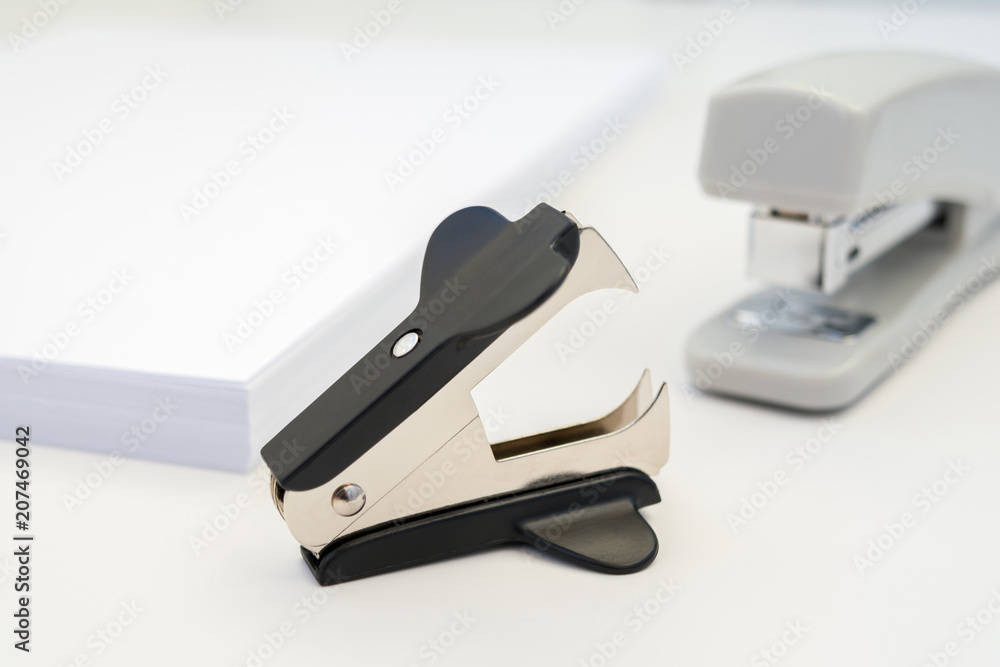 pile of office paper, black staple remover and gray stapler on white ...