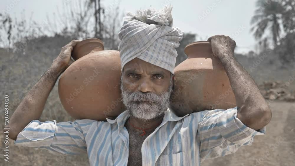 A displeased and intense man carrying two earthen pots on his each ...
