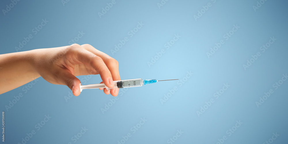 Female doctor hand holding syringe with blue background Stock Photo ...