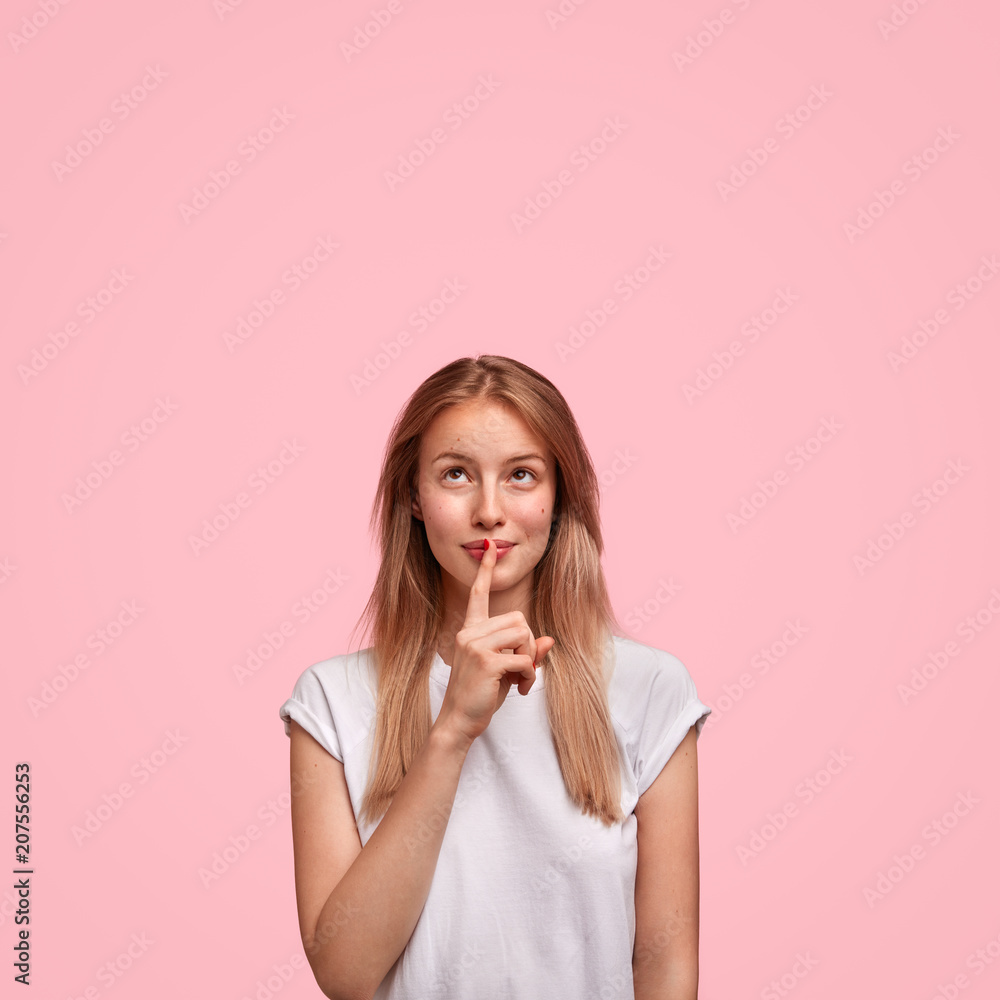 Pretty European young female shows silence sign and asks to keep ...