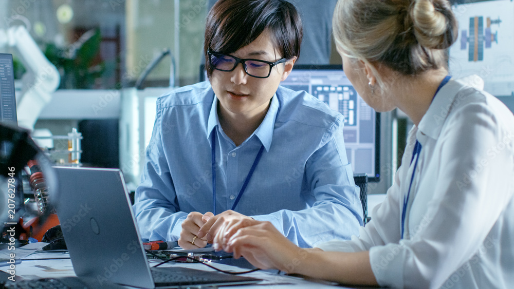 Two Computer Engineers Talking, They Connect Printed Circuit Board to a ...