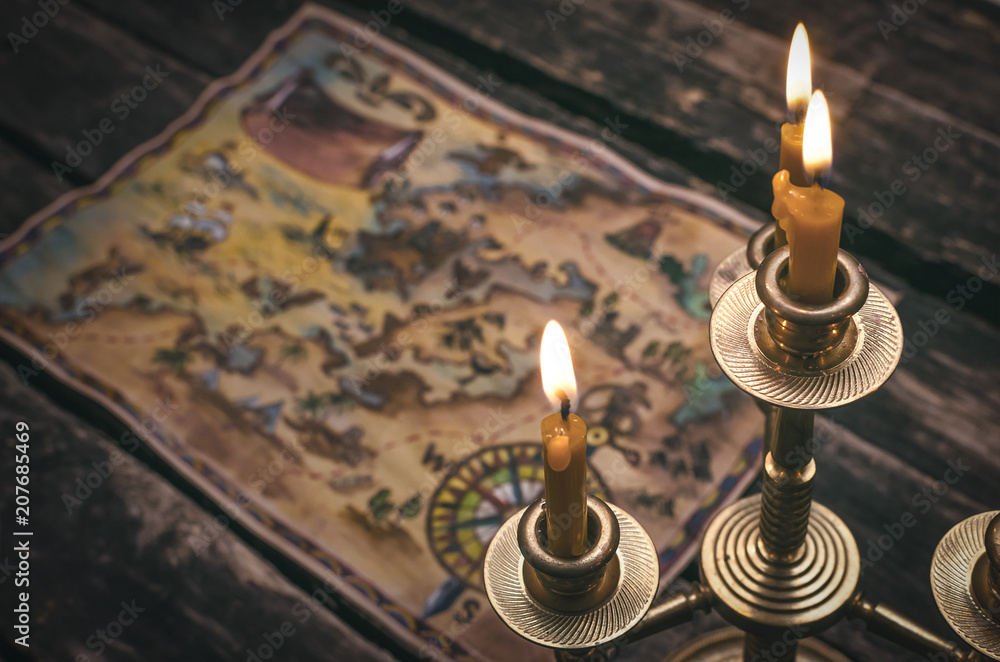 Pirate treasure map and burning candle on aged wooden table background ...