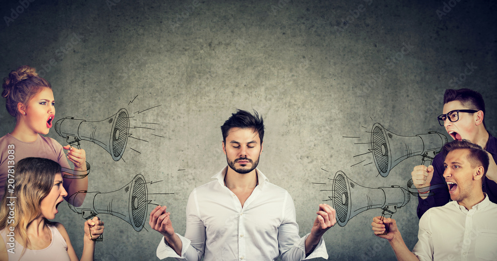 meditating businessman paying no attention to crowd of screaming angry ...
