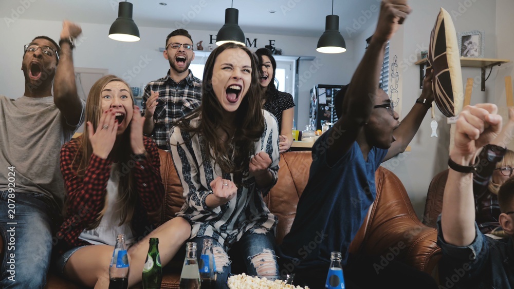 Foto de Multi-ethnic fans go crazy celebrating goal on TV. Passionate ...