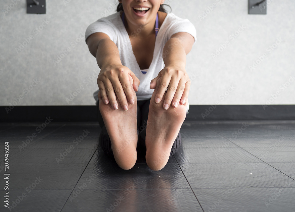Smiling active woman grabbing her feet to stretch hamstrings in the ...