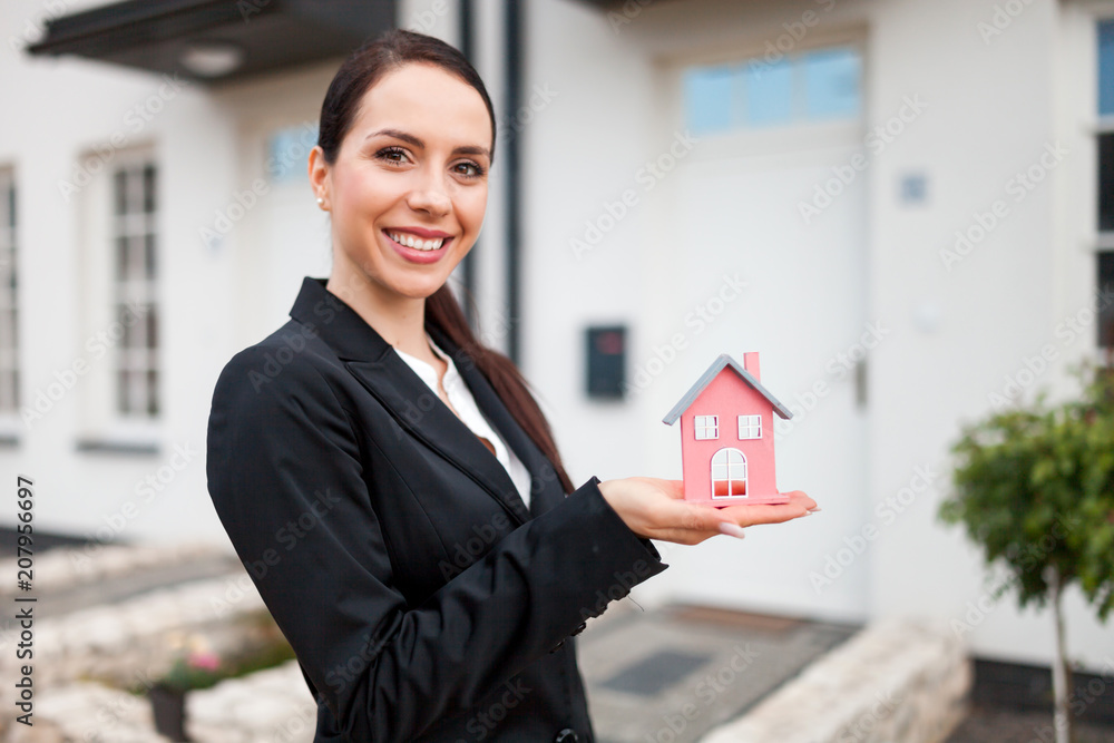 Real estate agent with model of house in front of home for sale, copy ...
