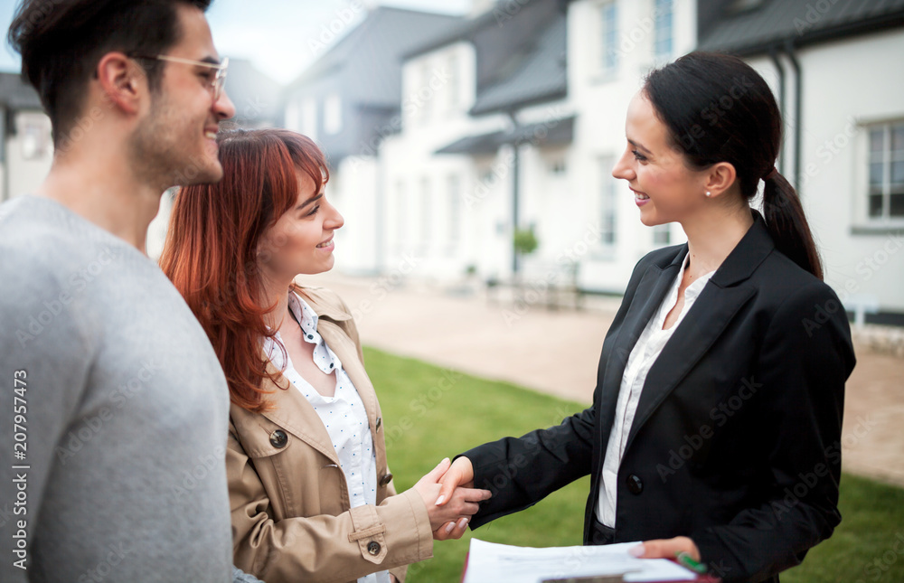 Real estate agent shaking hands with customers after buying new house ...