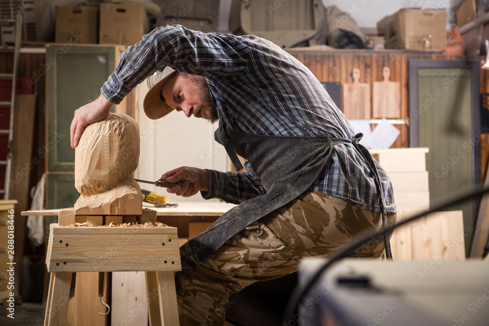Young man carpenter in a work clothes saws a man's head with a tree ...