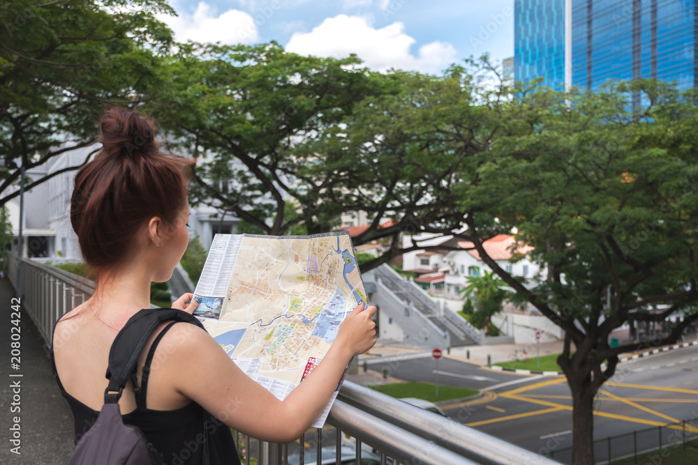 Young asian woman traveler holding map to find direction in Singapore ...