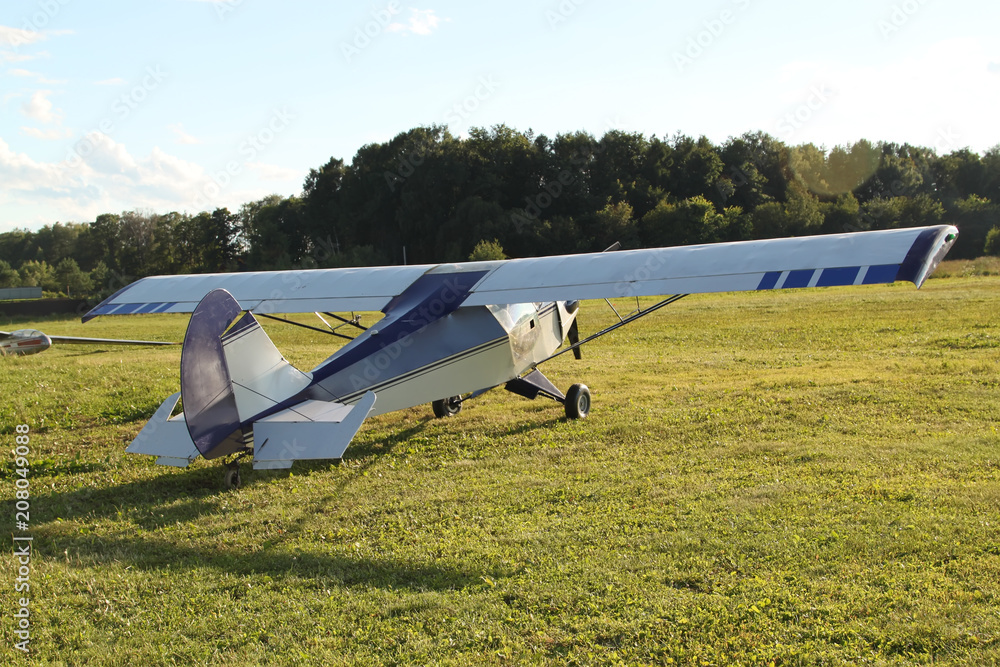 single-engine aircraft is on the field illuminated by sunlight in ...