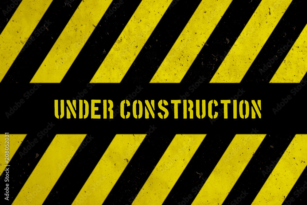 Under construction warning sign with yellow and black stripes painted ...