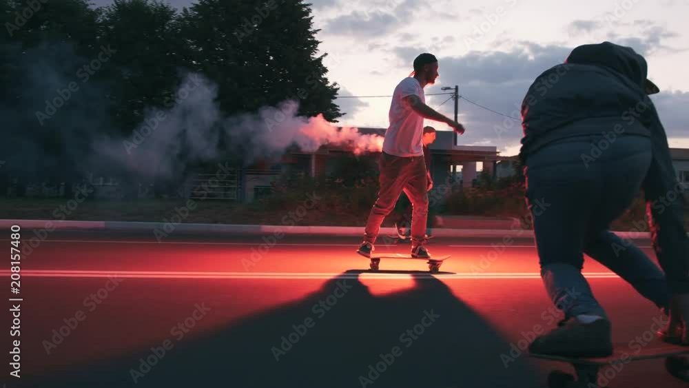 Group of young people skateboarding on the road in the early ...