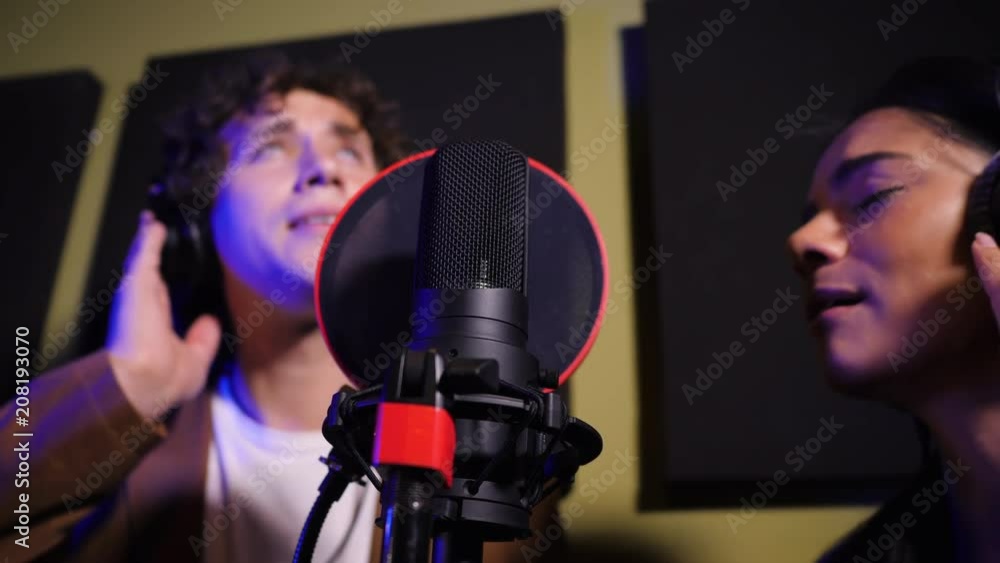 Two young singers performing their song in record studio. Professional ...
