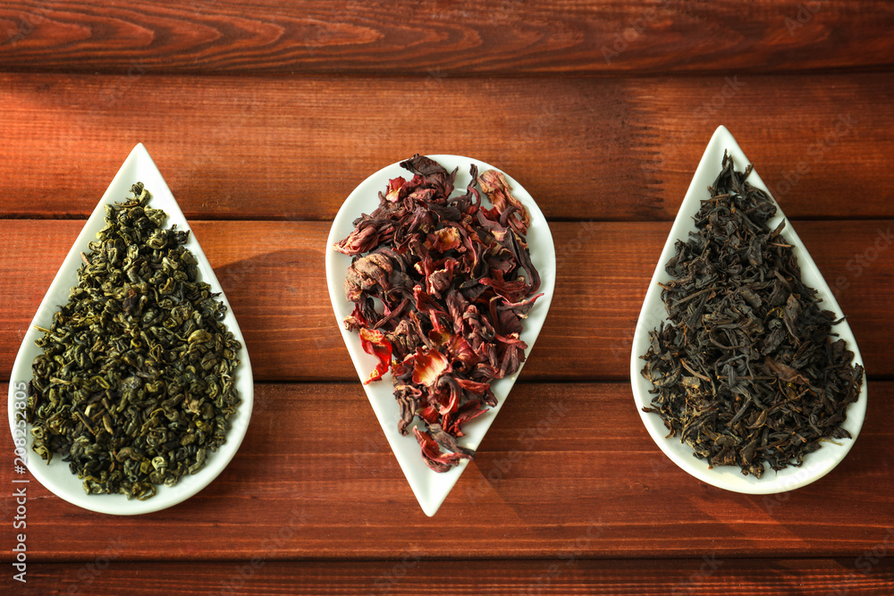 Variety of dry tea in plates on wooden background Stock Photo | Adobe Stock