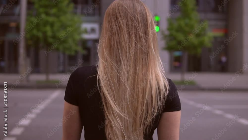 back view woman wearing black dress with long blond hair walking on ...