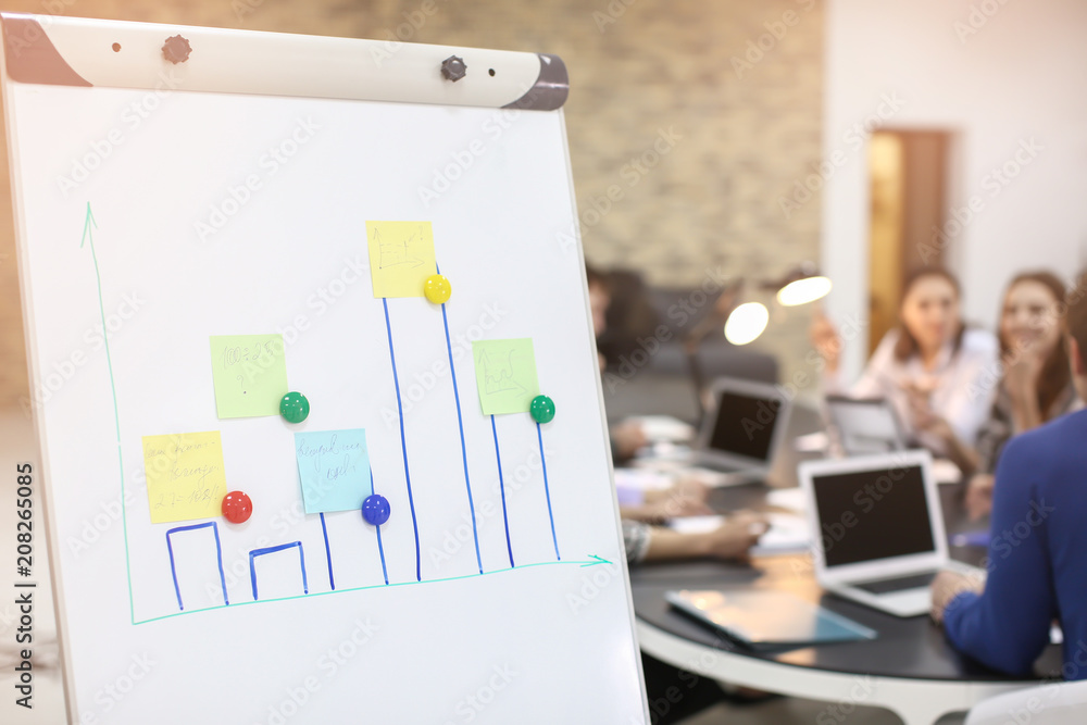 Flip chart and office employees on background. Business meeting Stock ...